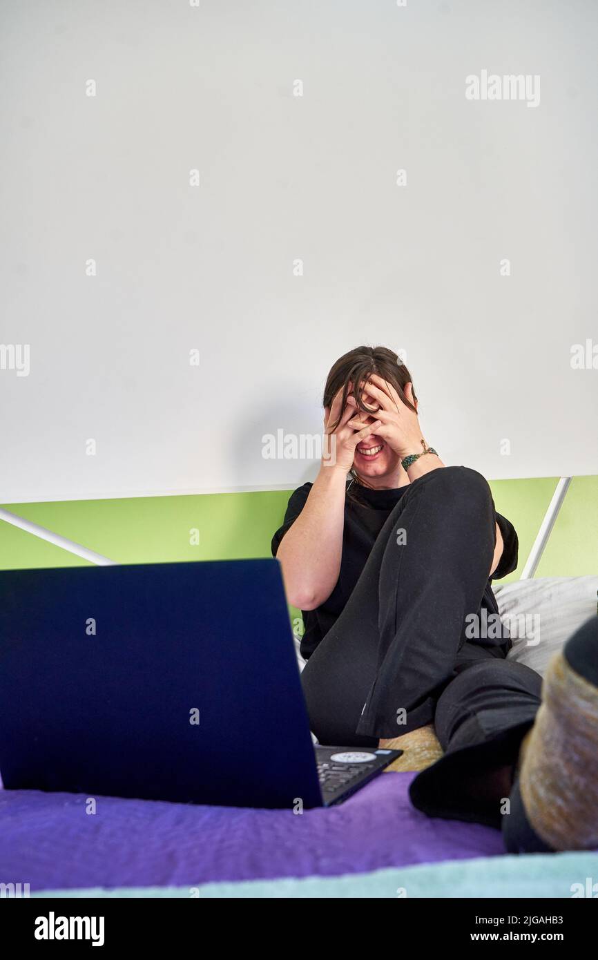 A vertical shot of Caucasian woman with scared face looking at computer ...