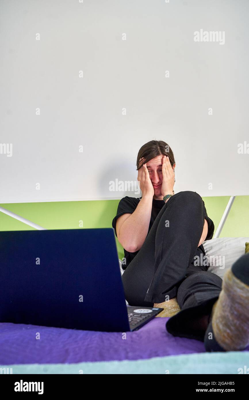 A vertical shot of Caucasian woman with scared face looking at computer ...