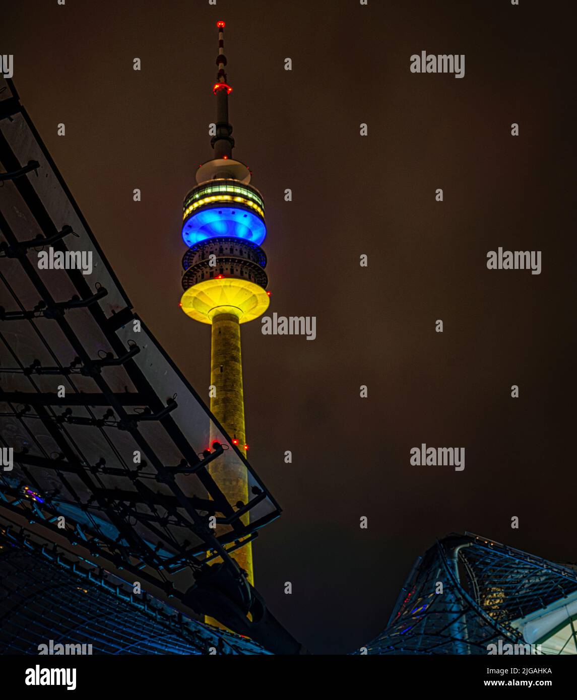 A low angle shot of Munich Olympic tower illuminated with national ...
