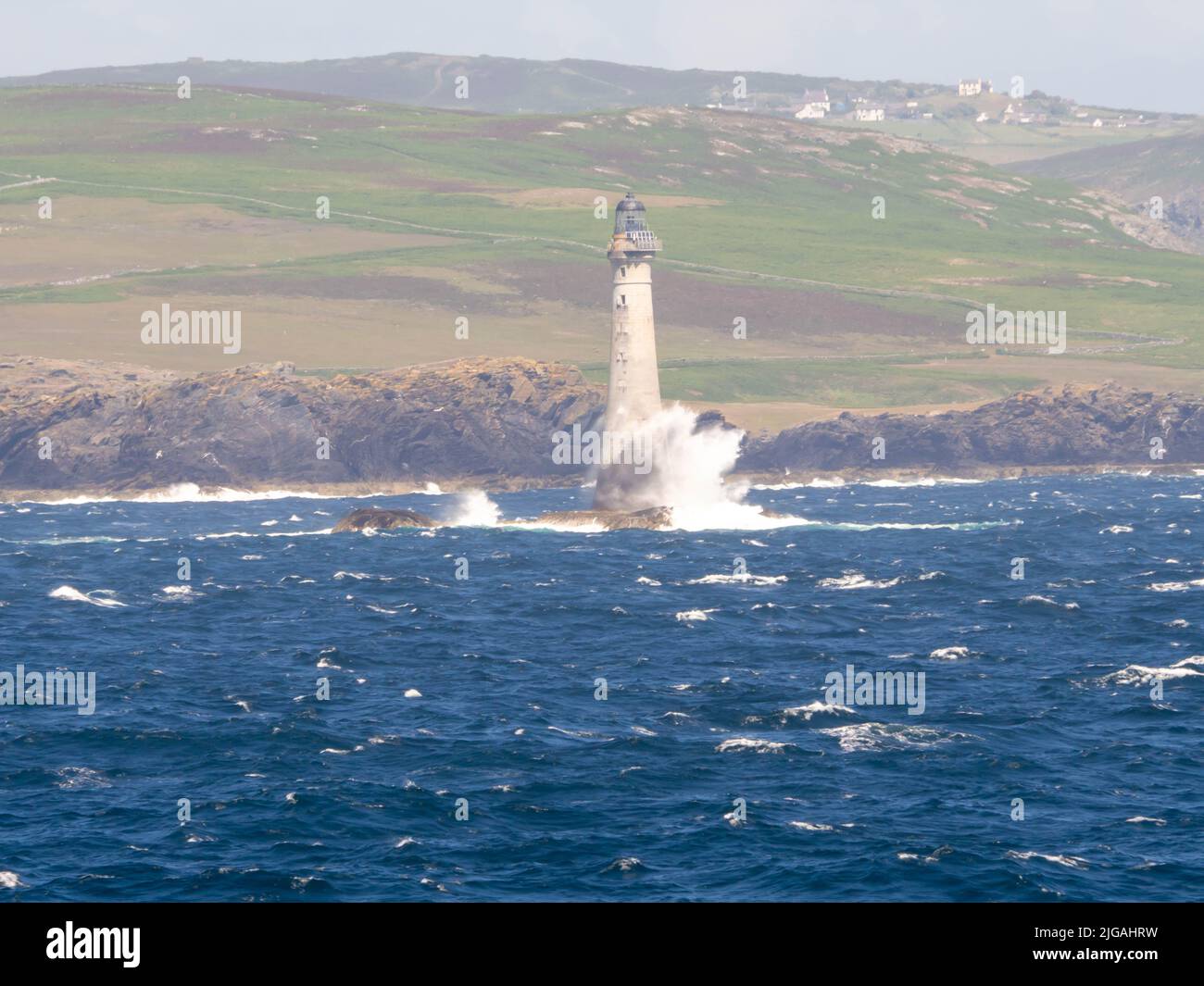 Huge white waves crashing waves up a white lighthouse just off the ...