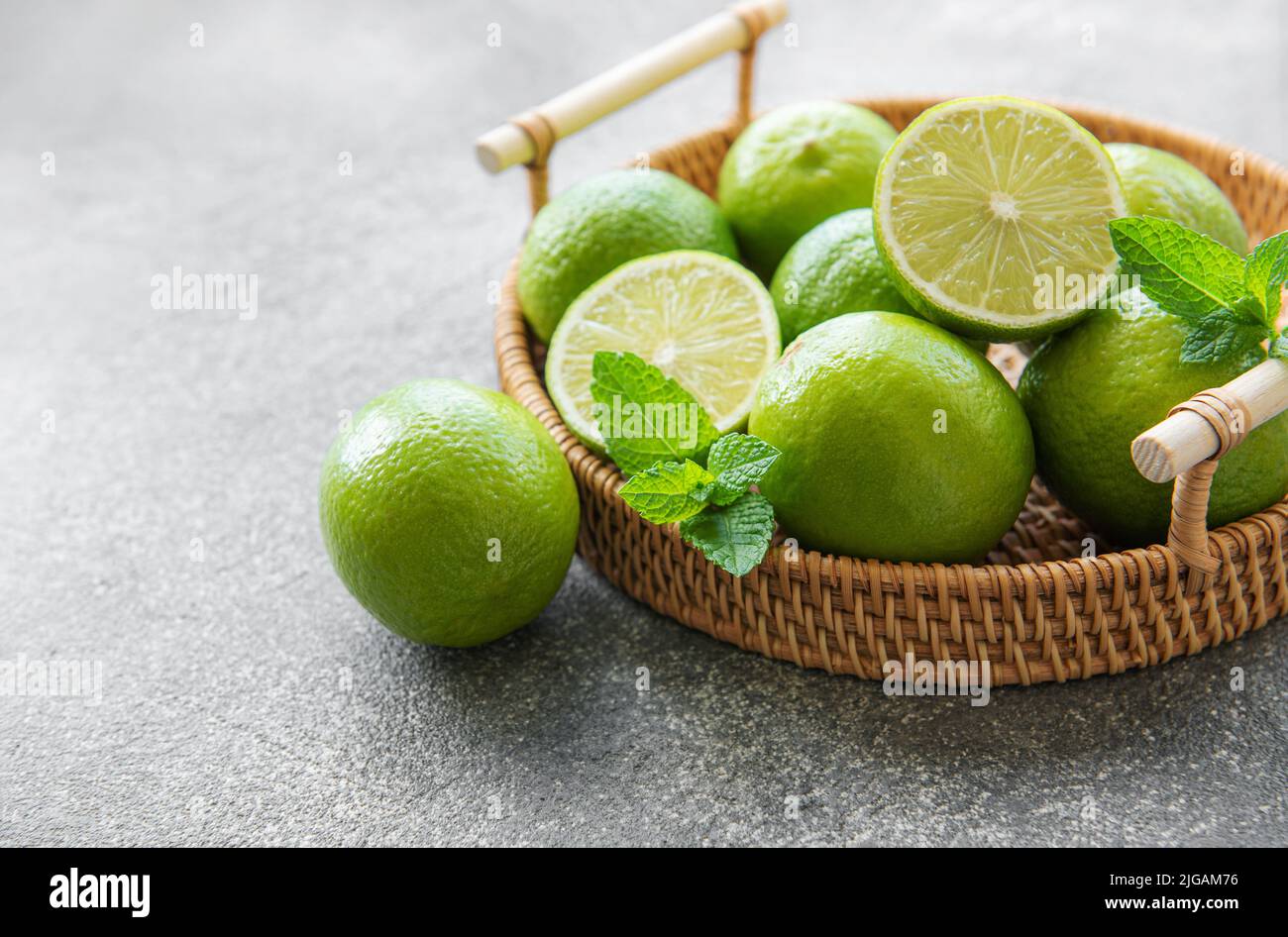 Green Limes with fresh mint leaves on wicker tray, concrete background Stock Photo - Alamy