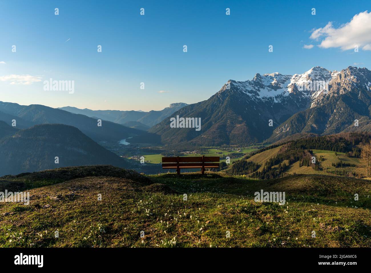 A scenic view of a bench against snowy mountains covered with green ...