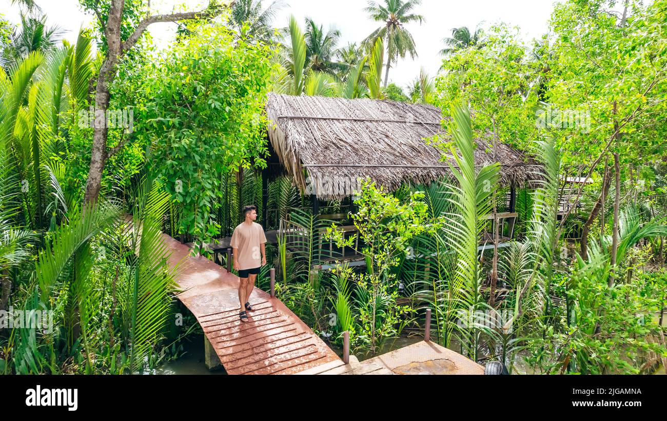 young man walking down pier near mekong delta river in Ben Tre Vietnam ...