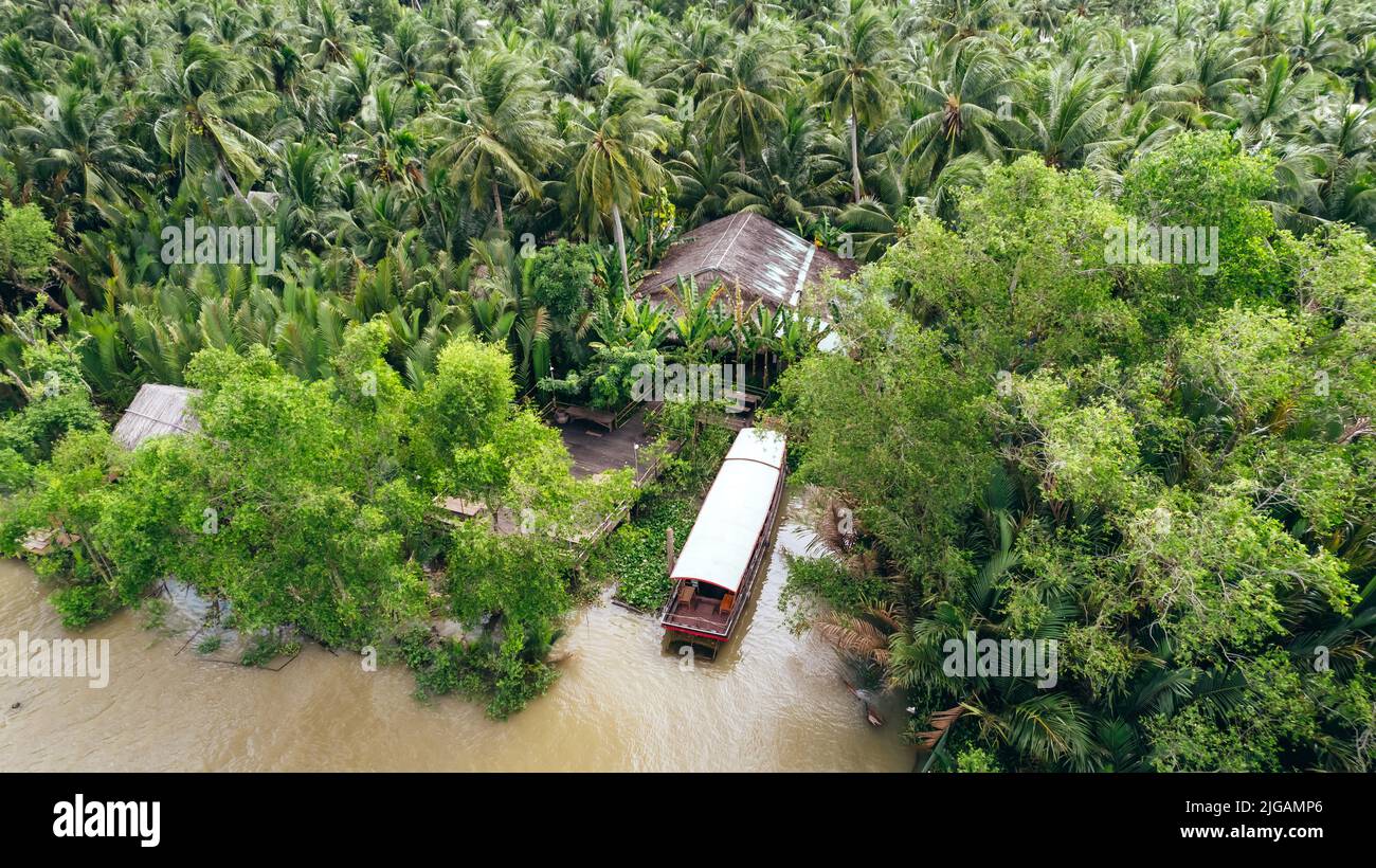 aerial top down view of boat docked at pier along brown mekong delta ...