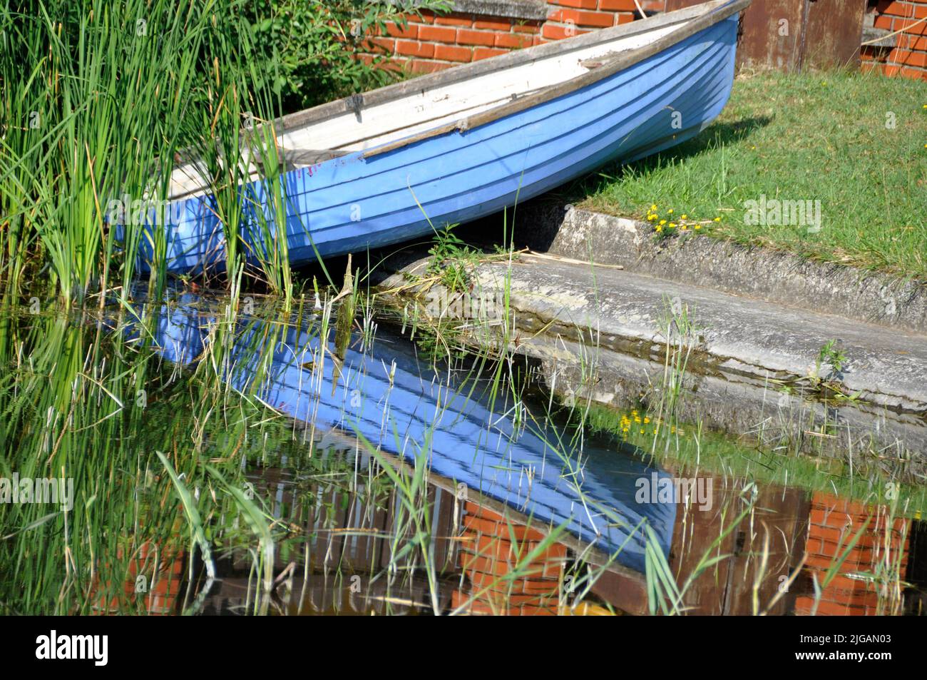blue fishing boat reflection in the water Stock Photo - Alamy