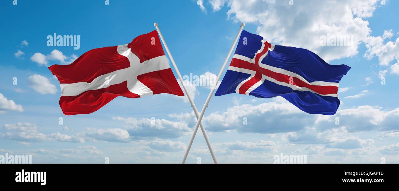 two crossed flags Iceland and Denmark waving in wind at cloudy sky ...