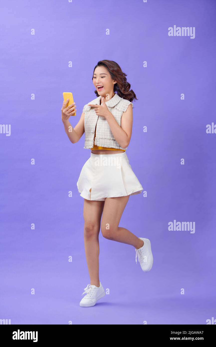 Excited cheerful woman holding cell phone in hand pointing at screen ...