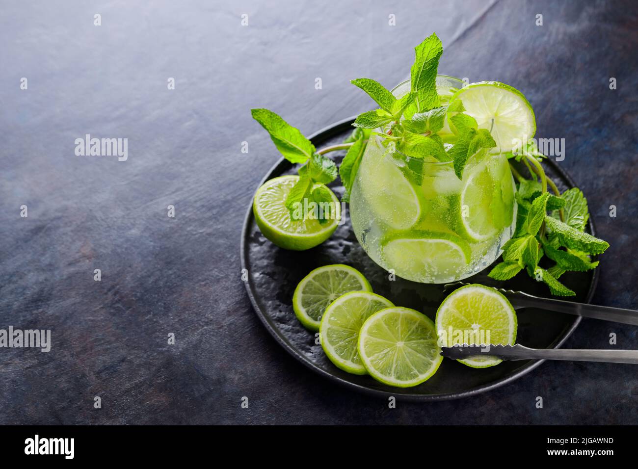 Mojito cocktail, mint and lime slices on a dark background. Summer ...