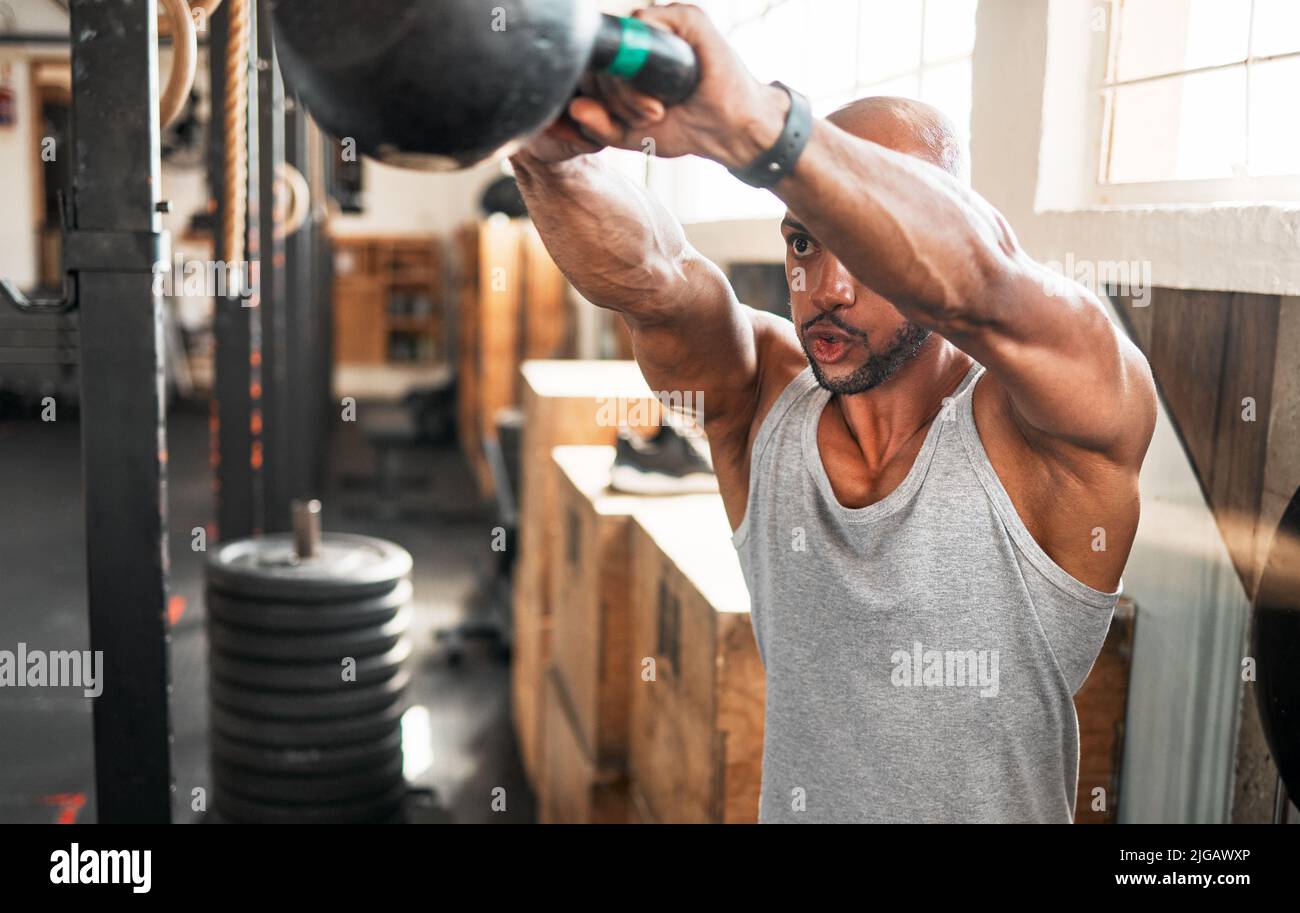 Swing hard and high. a young man doing kettlebell swings during his ...