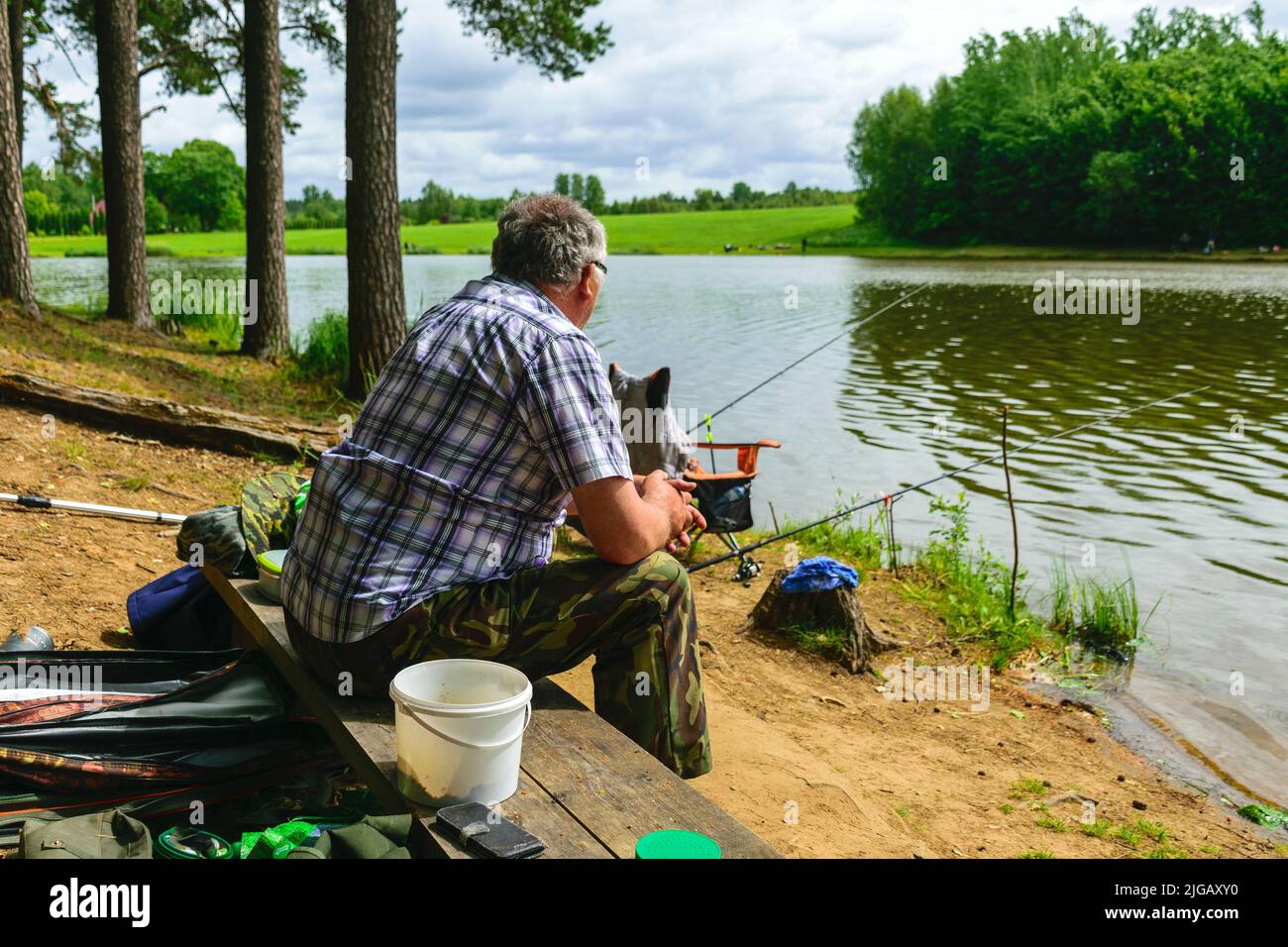 sunny photo from summer with an angler, angler sits on the shore of the ...
