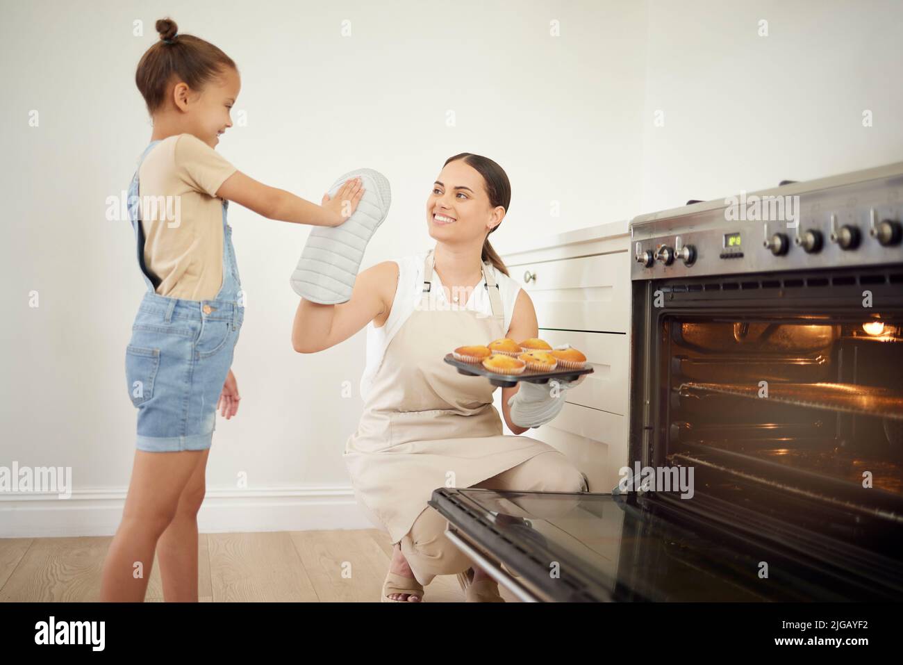 Another successful batch. a young mother and daughter giving each other a high five while baking ...