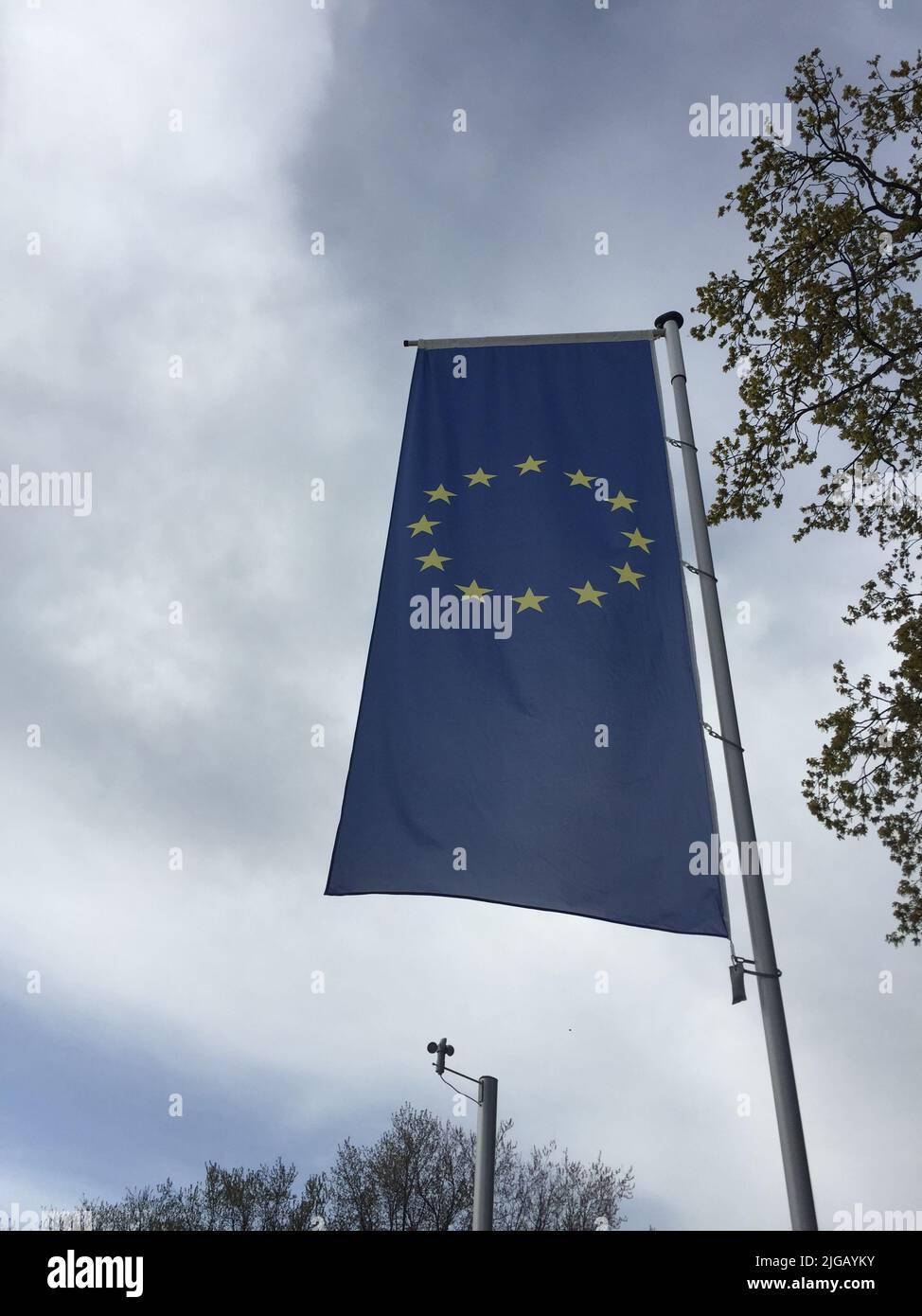 A vertical shot of the Europe flag on a pole with clouds in the ...