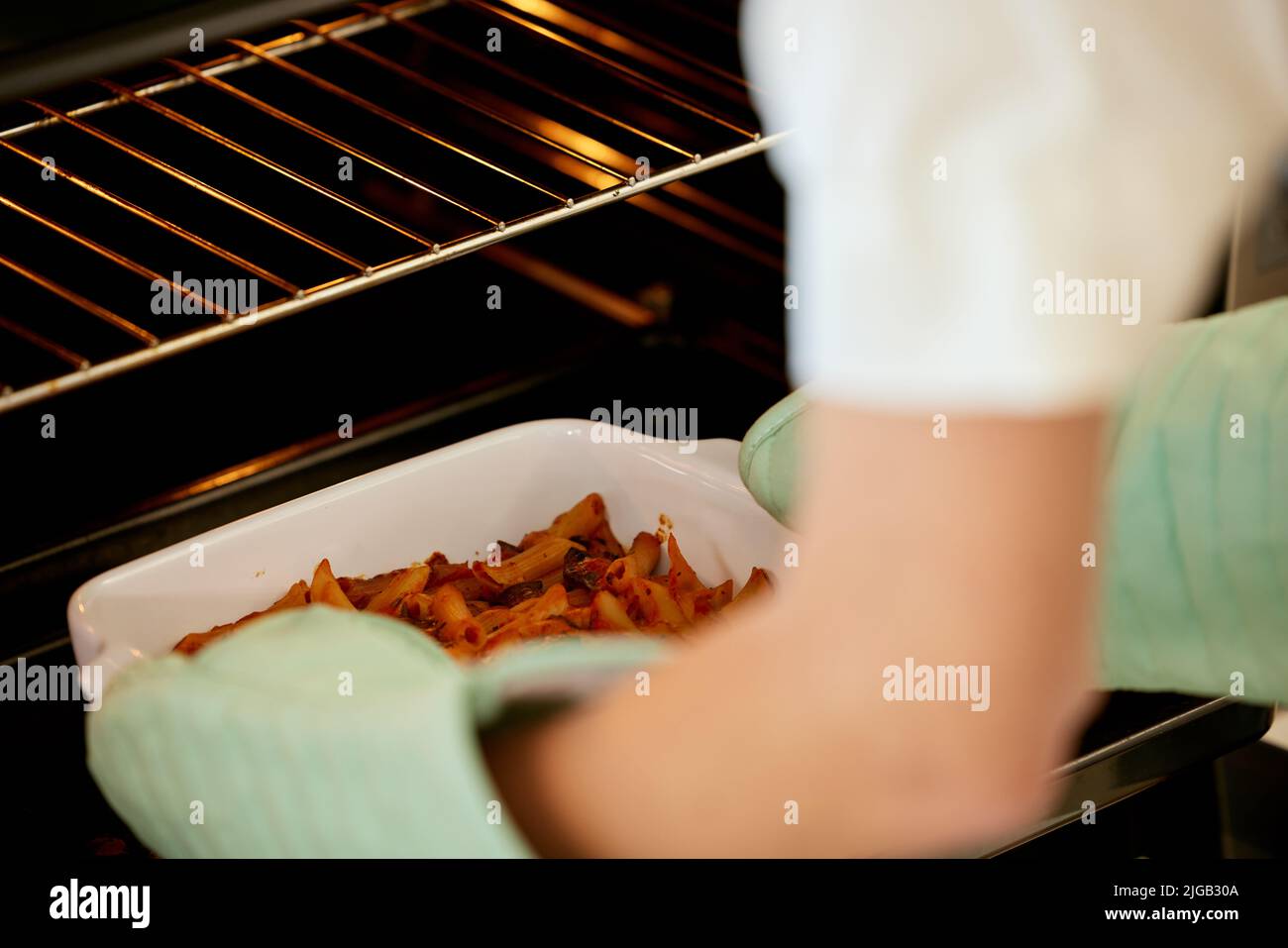 Its ready to go. an unrecognizable person removing food from an oven at ...