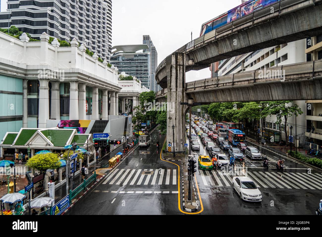 A BTS Skytrain passes over heavy car traffic outside of Erawan Shrine ...