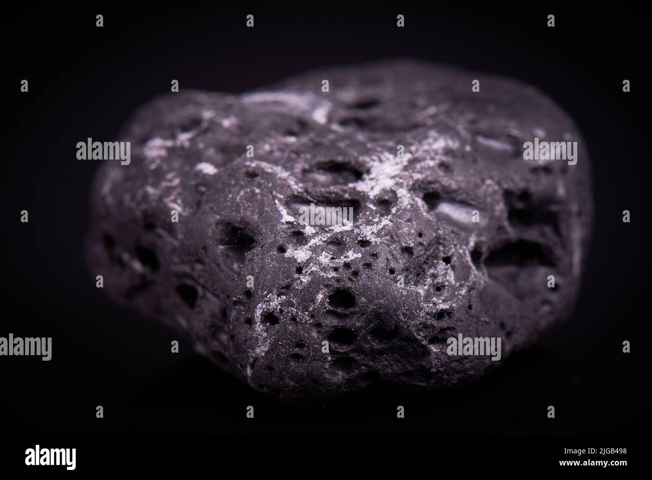 Black porous basalt stone on a black background Stock Photo - Alamy