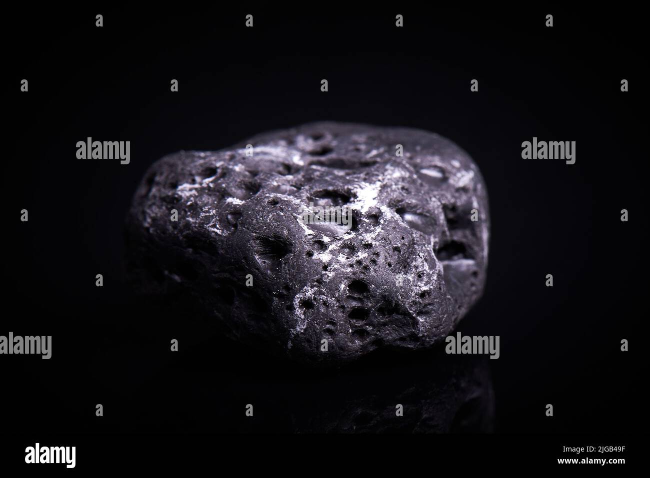 Black porous basalt stone on a black background Stock Photo - Alamy