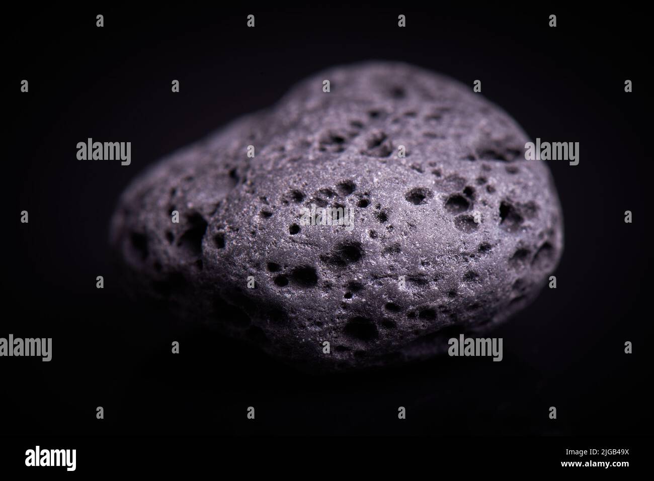 Black porous basalt stone on a black background Stock Photo - Alamy