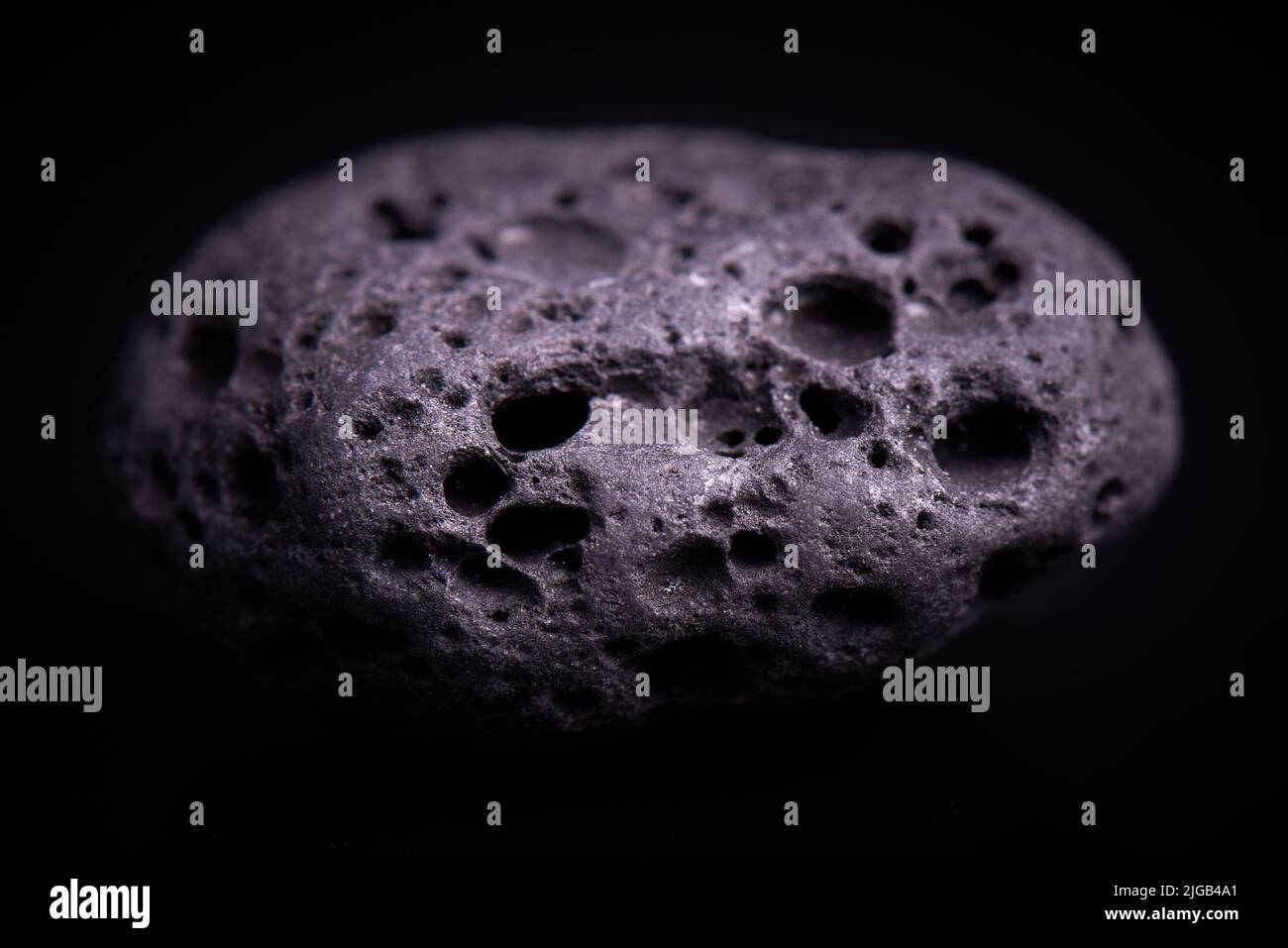 Black porous basalt stone on a black background Stock Photo - Alamy