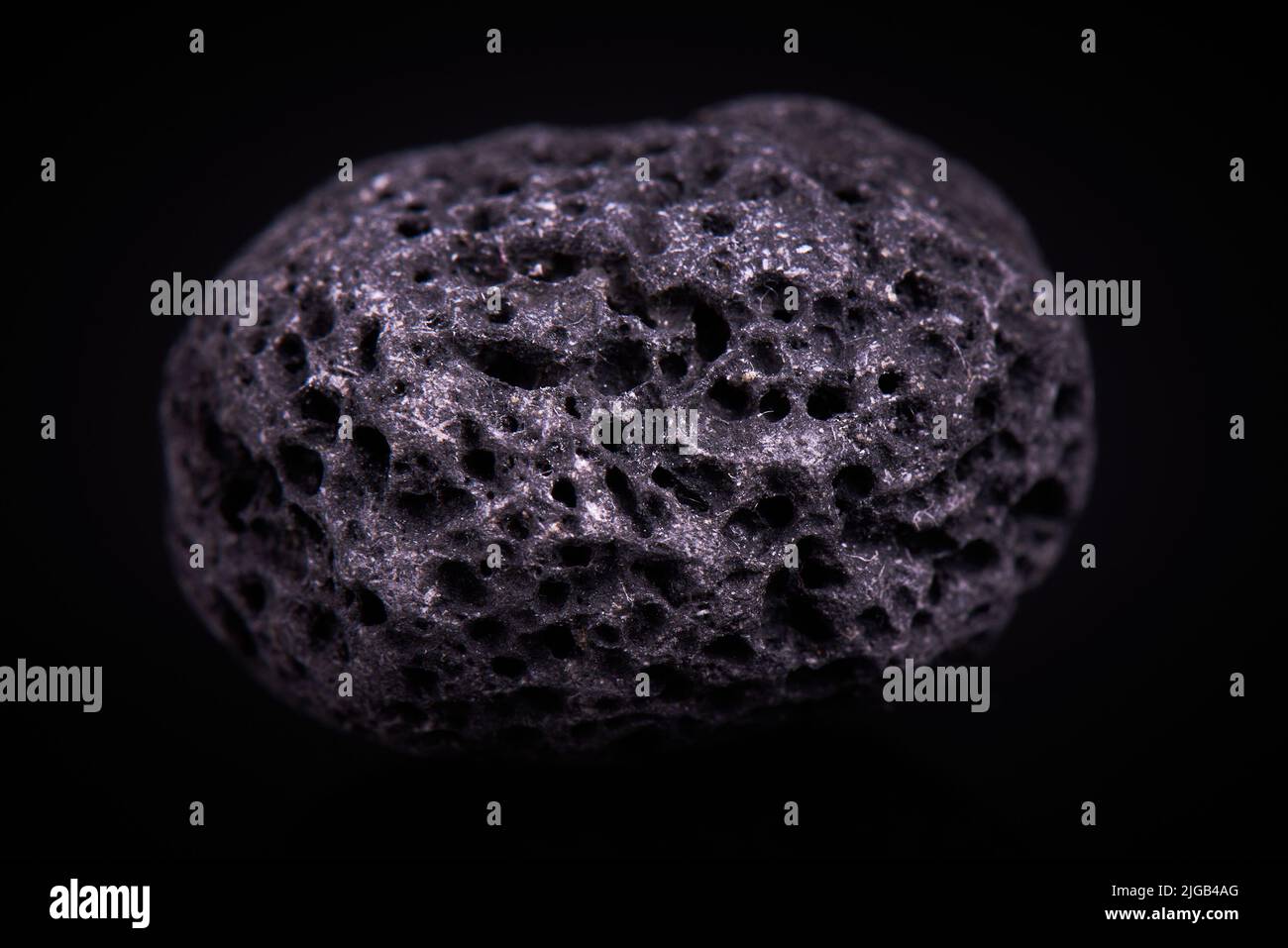 Black porous basalt stone on a black background Stock Photo - Alamy