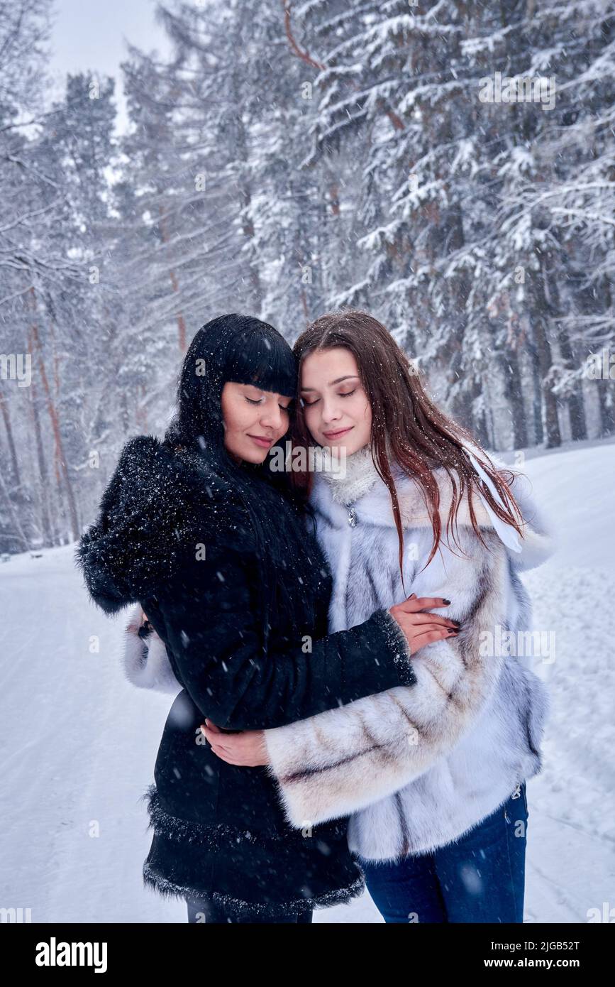 Two girls in a black and white coat in a winter park Stock Photo - Alamy