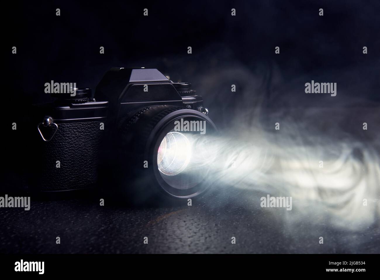 old camera with a ray of light from the lens in the smoke on a black ...