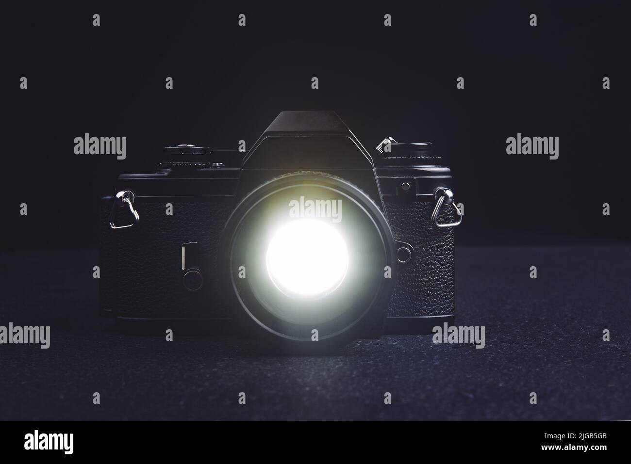 old camera with a ray of light from the lens in the smoke on a black ...