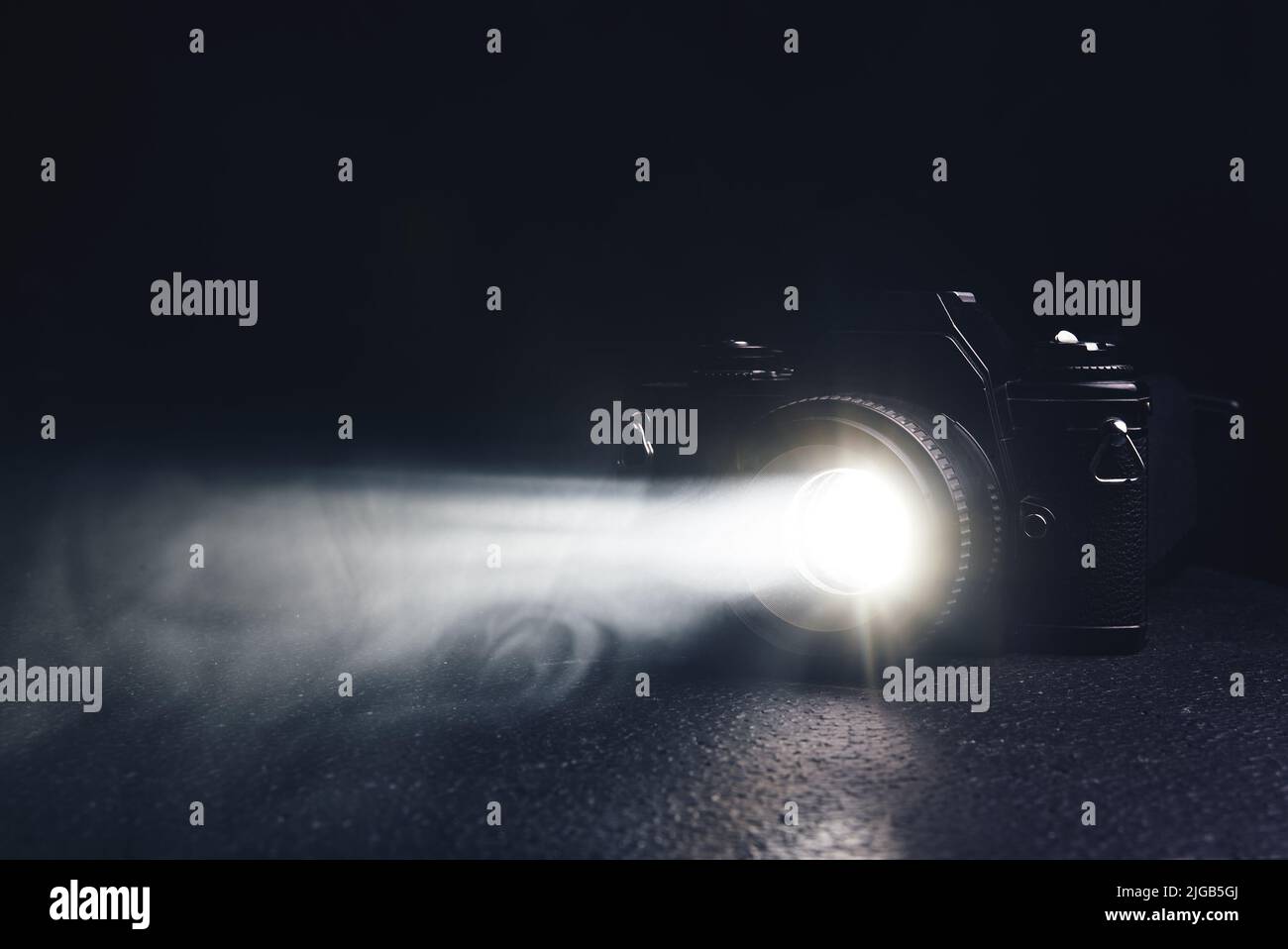 old camera with a ray of light from the lens in the smoke on a black ...