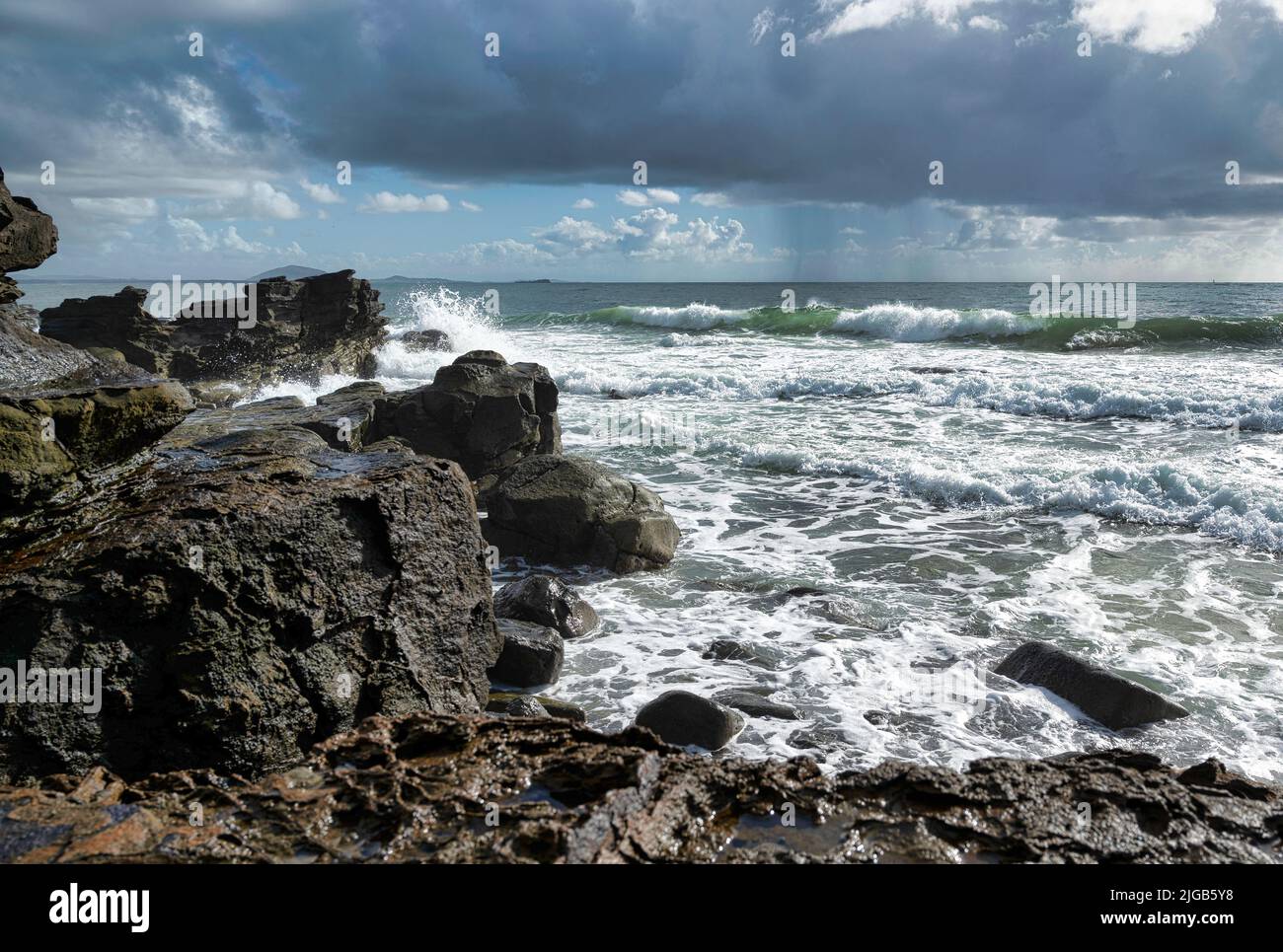 An aerial view of rocky beach in background of growing trees in ...