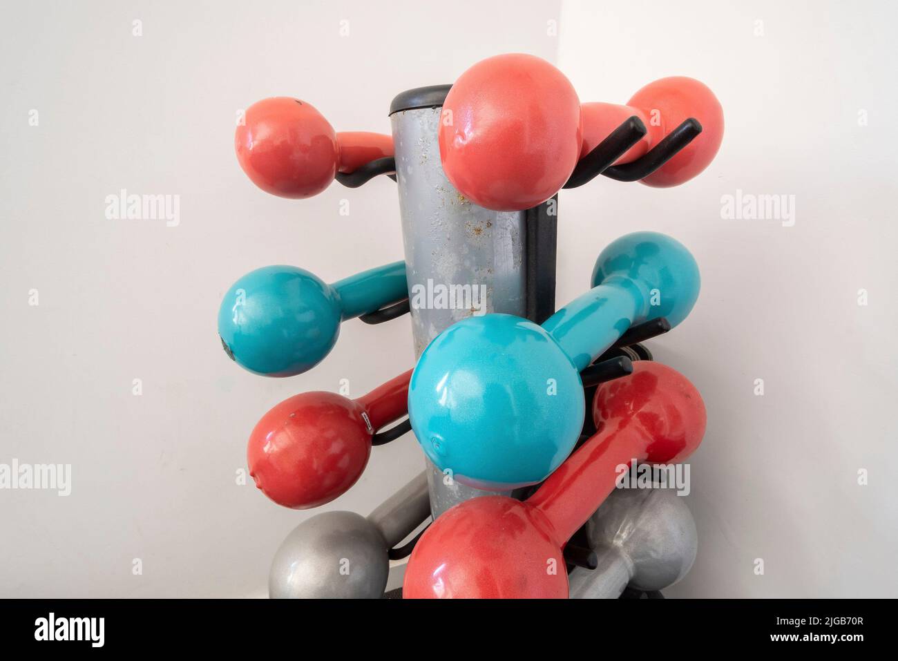 assorted colored isolated dumbbell on stand, front view Stock Photo - Alamy