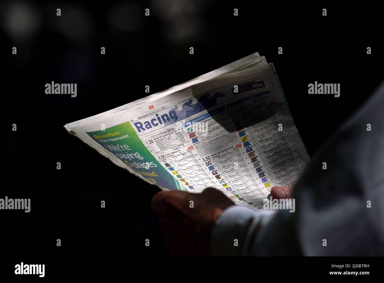 A racegoer checks the race card in the Daily Express newspaper on ...