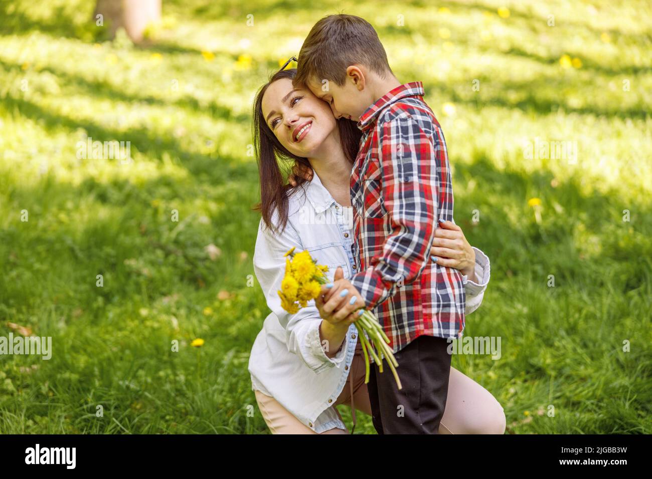 Small cute boy hugging mother and giving flowers. Woman getting ...