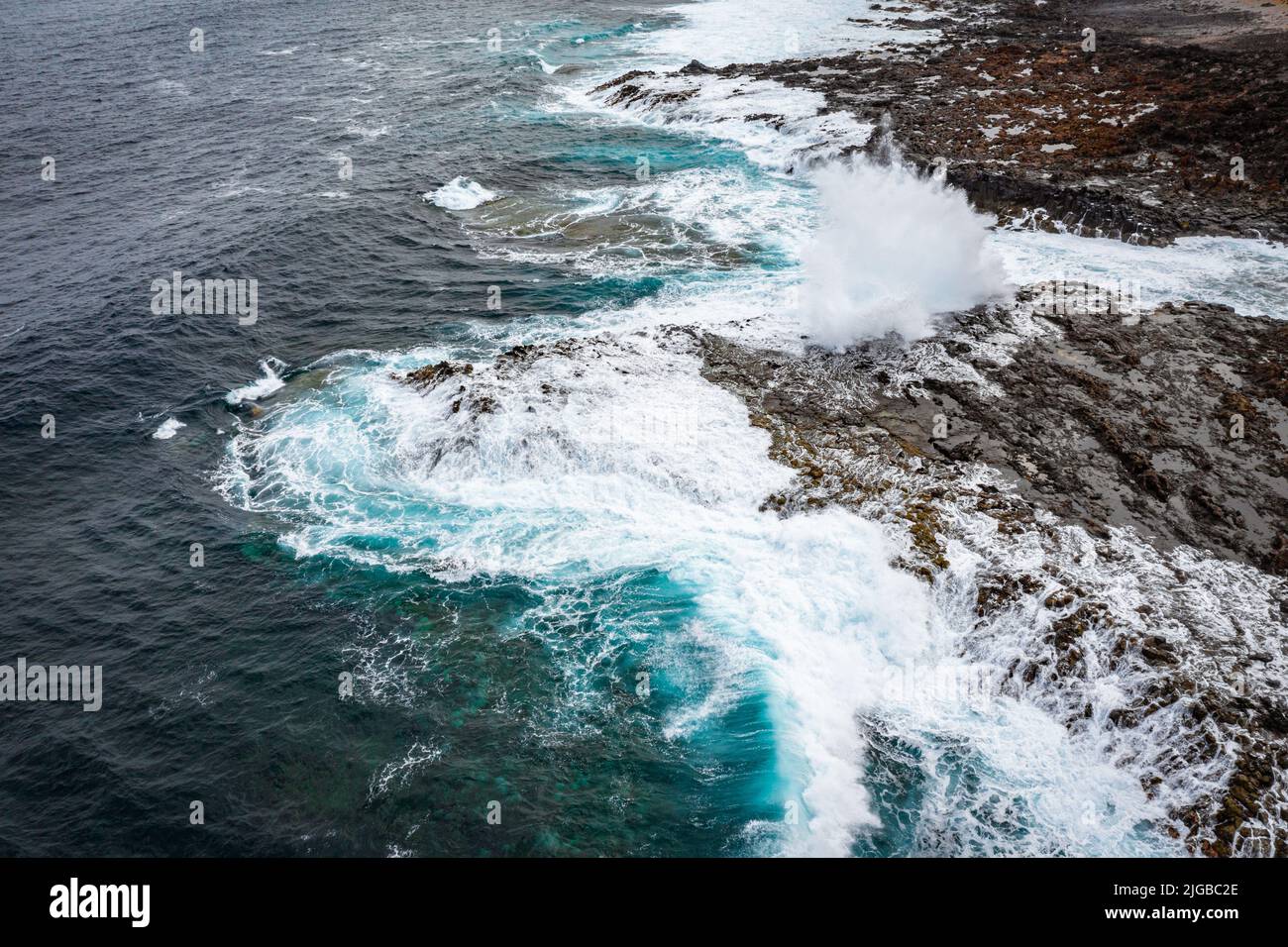 ocean waves crashing on the rocks with mountains and village in ...