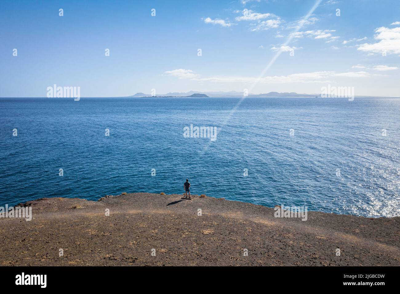 man standing on edge of a cliff with islands on horizon Stock Photo - Alamy