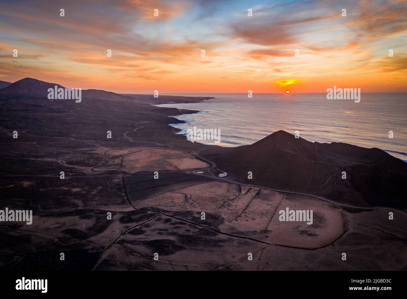 aerial view of volcanic landscape with volcano at coast during sunset ...