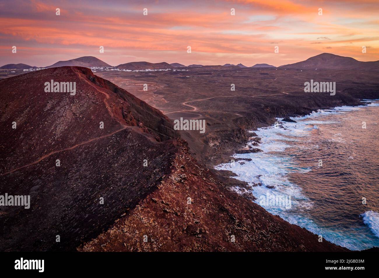 aerial view of volcanic landscape with volcano at coast during sunset ...