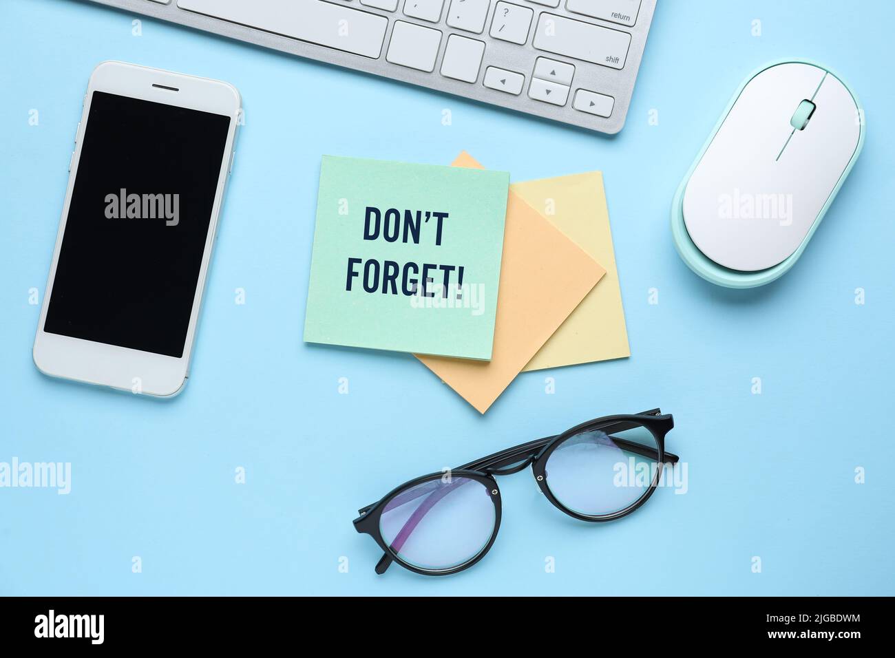 Smartphone, computer, paper with text DON'T FORGET and glasses on light ...