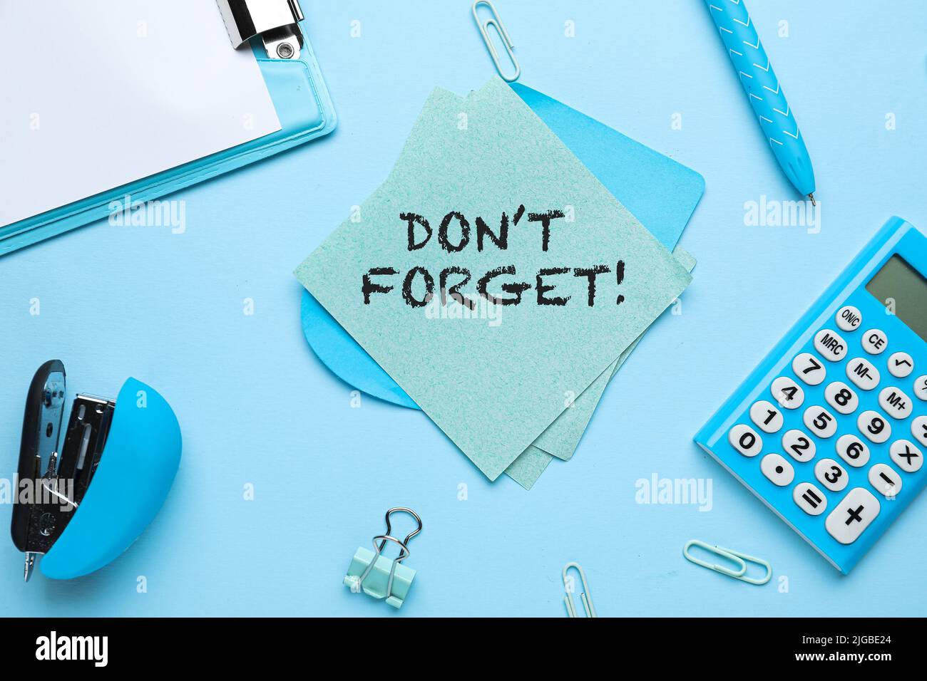 Sticky note with text DON'T FORGET and stationery on light blue ...