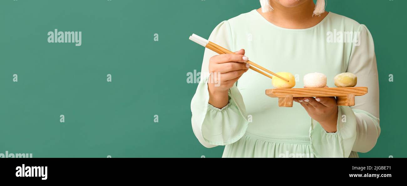 Asian woman eating tasty Japanese mochi on green background with space ...