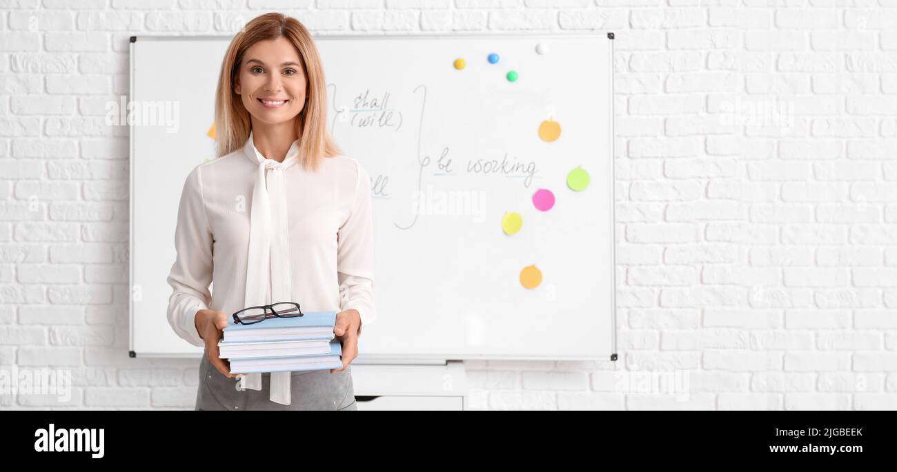Beautiful English teacher with books in classroom Stock Photo - Alamy