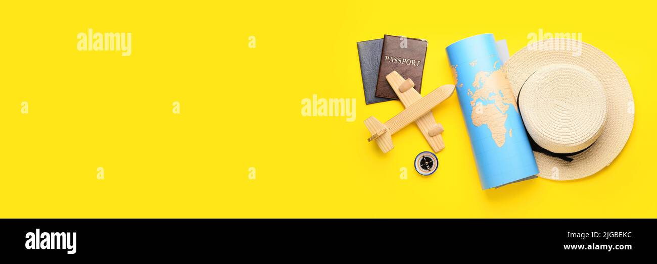World map, hat, compass, wooden airplane and passports on yellow ...