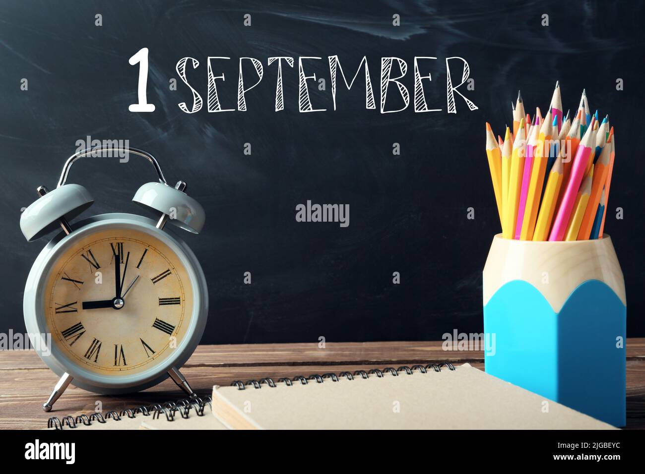 Set of school stationery and clock on table in classroom. Time to study ...