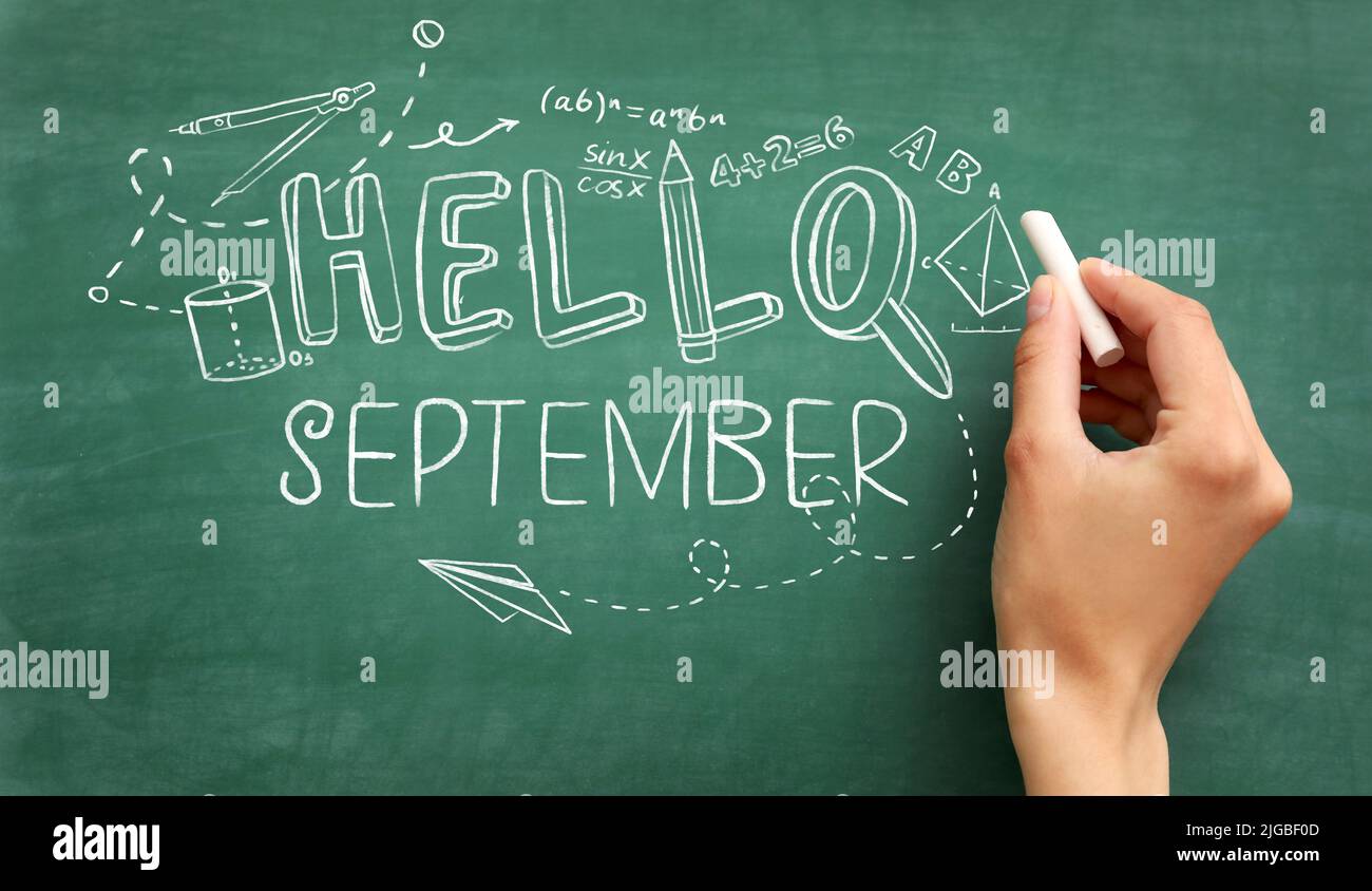 Woman's hand with chalk writing text HELLO, SEPTEMBER on school ...