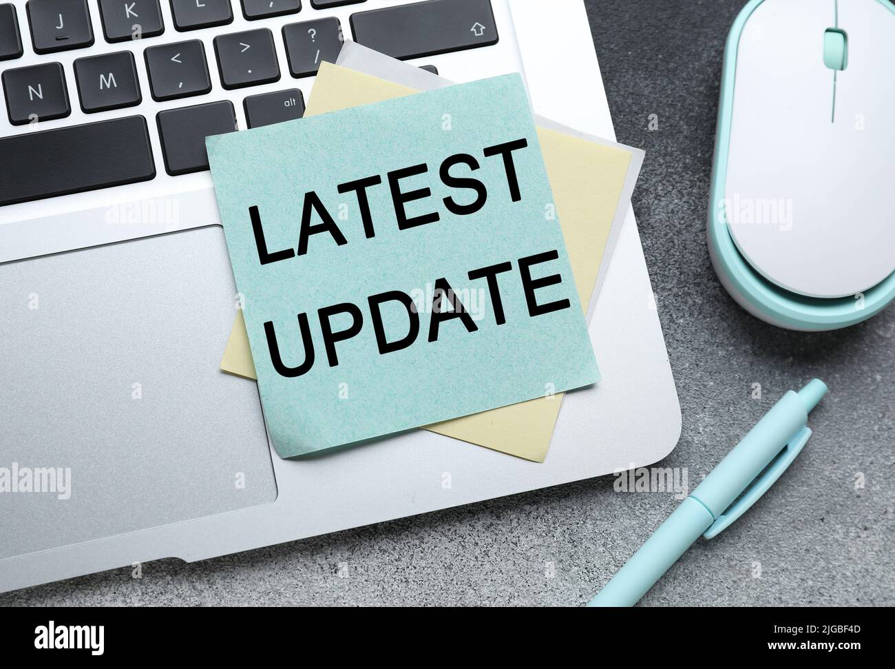 Laptop, mouse and note paper with text LATEST UPDATE on grey background ...