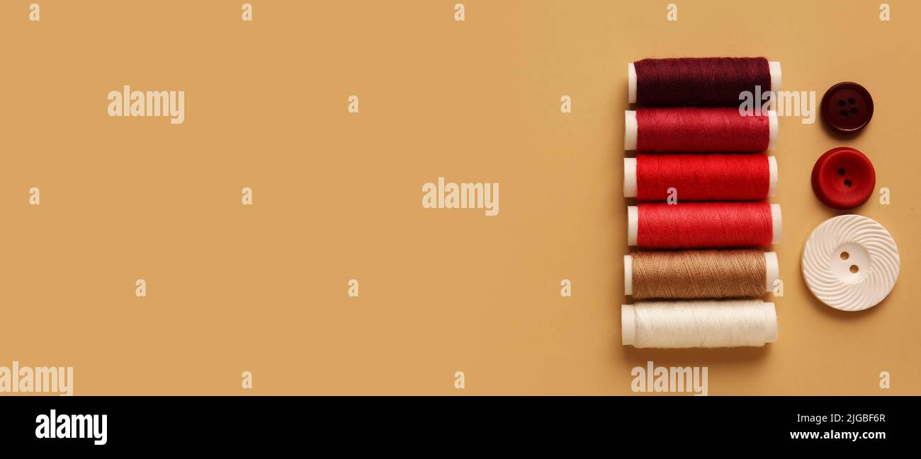 Colorful sewing threads and buttons on beige background with space for ...