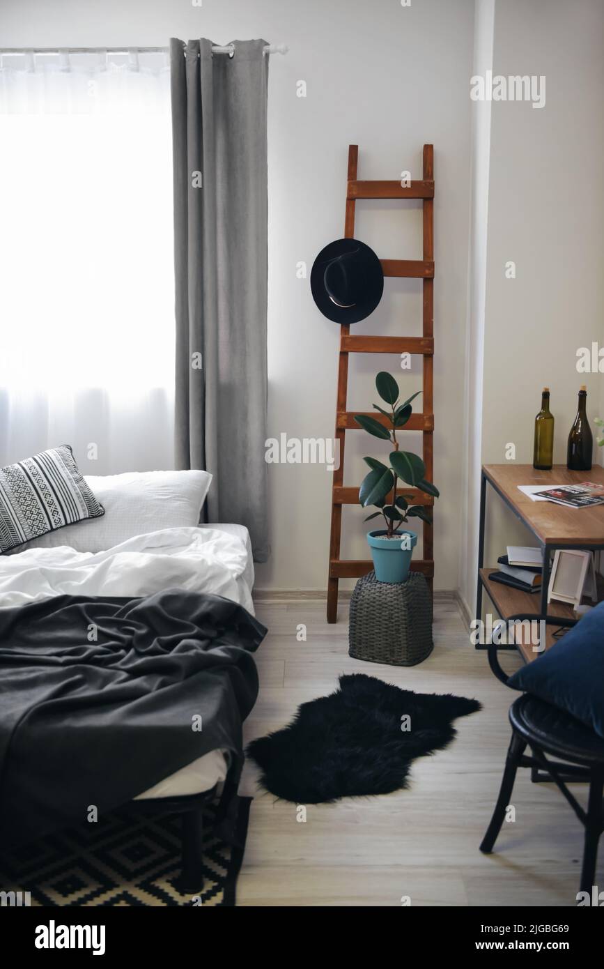 Interior of stylish bedroom with ladder and shelving unit Stock Photo ...