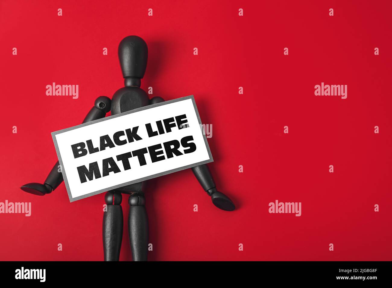 Black mannequin and paper sheet with text BLACK LIFE MATTERS on color ...