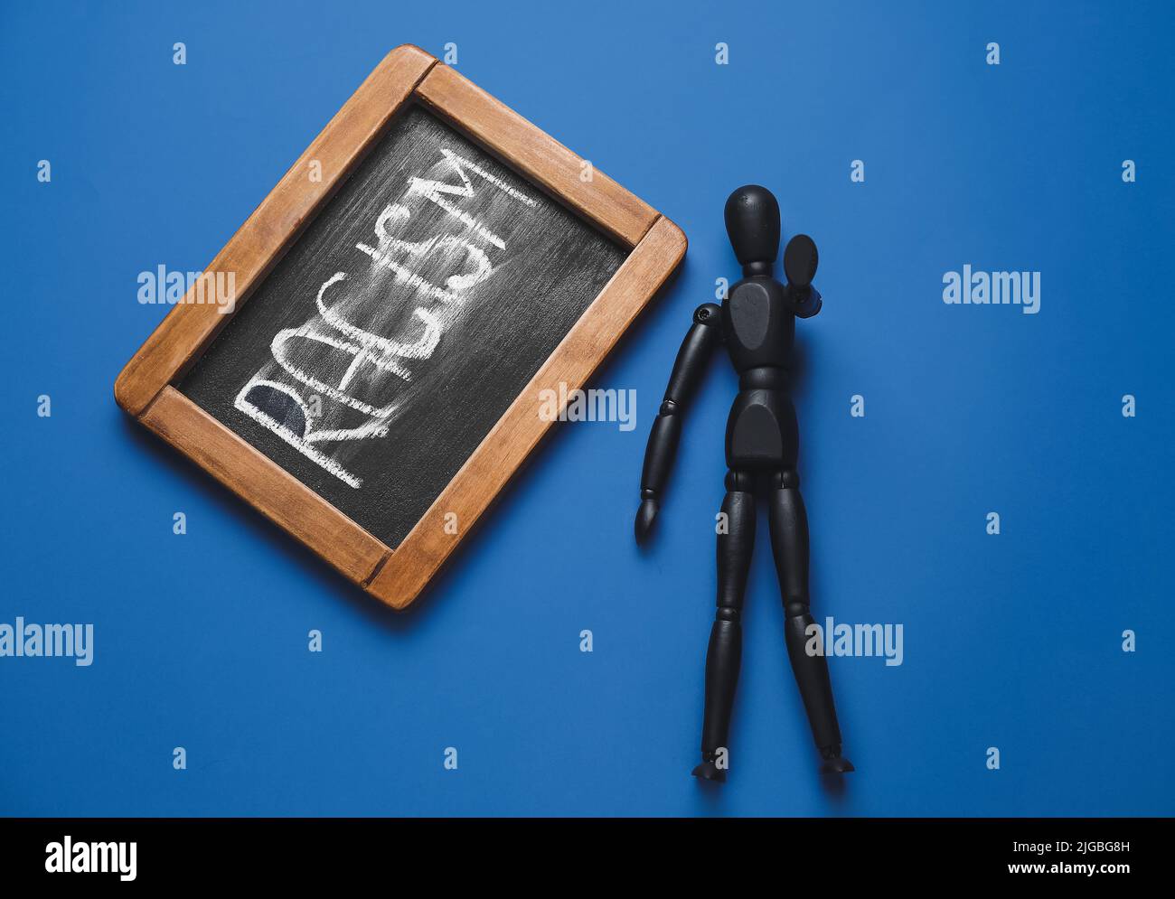 Chalkboard with written word RACISM and black mannequin on color ...