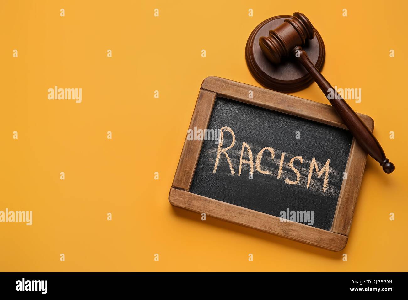 Chalkboard with written word RACISM and judge gavel on color background ...