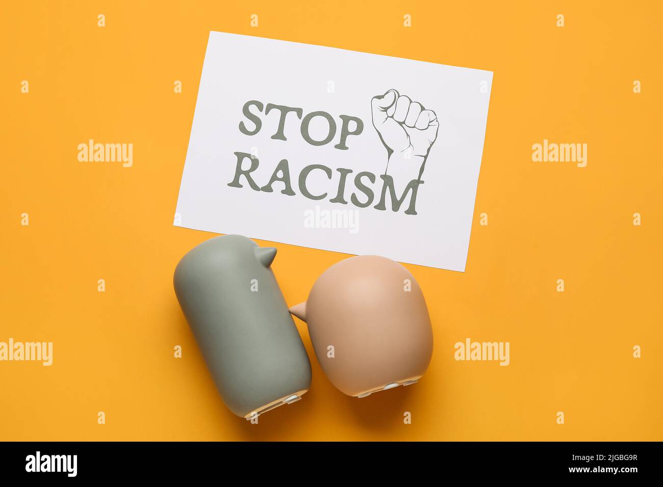 Figurines of birds and paper sheet with text STOP RACISM on color ...