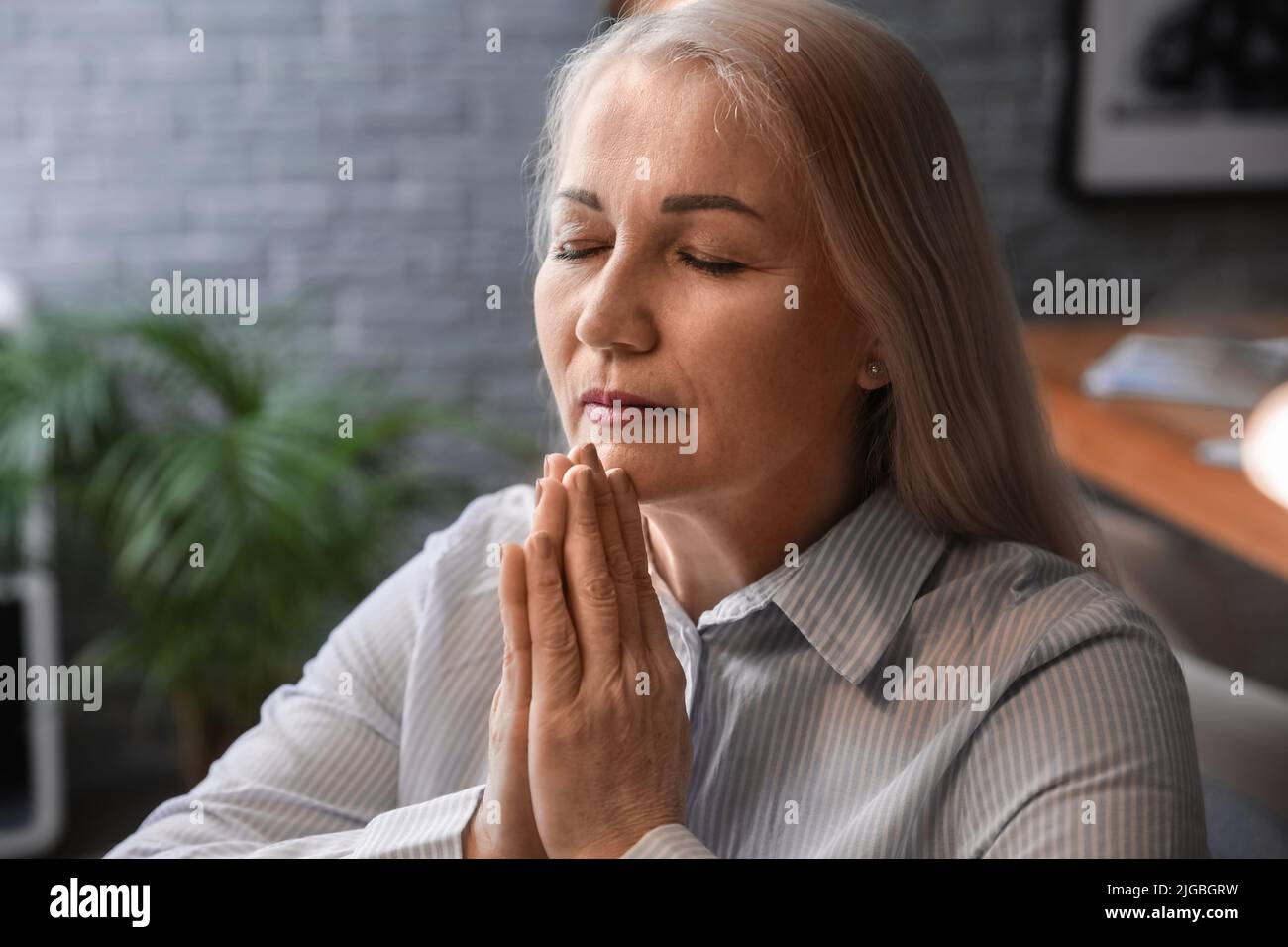 Religious mature woman praying in room Stock Photo - Alamy